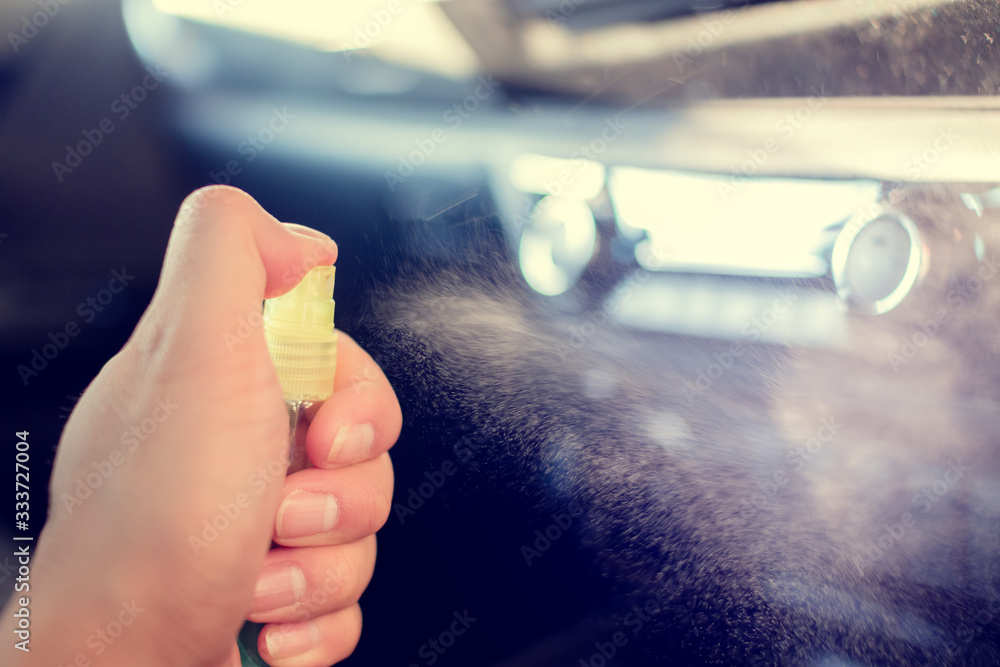 Hand of lady that spraying alcohol,disinfectant on car interior in her ...
