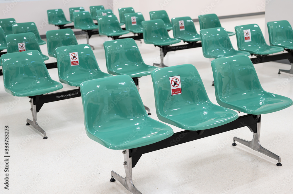 Row of empty green chairs and no sitting sign for patient waiting ...