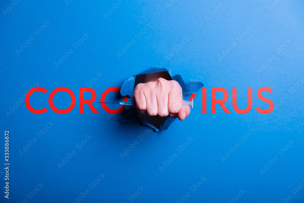 Human hand breaking a blue paper, in the hand is a syringe with the ...