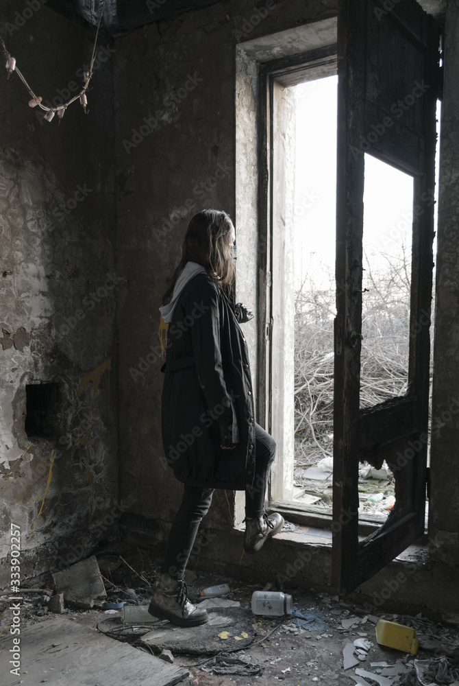Teenager girl in a black medical mask in an abandoned post-apocalyptic ...