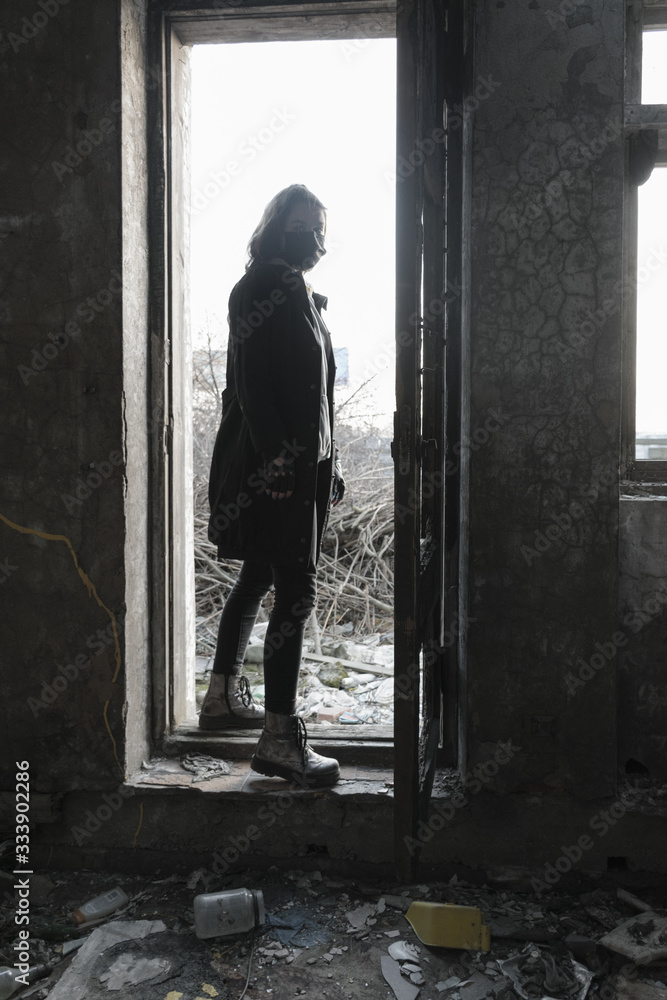 Teenager girl in a black medical mask in an abandoned post-apocalyptic ...