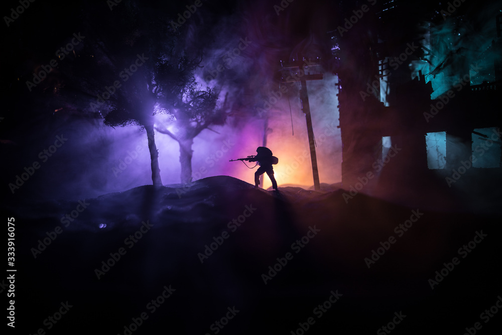 Army sniper with large caliber rifle standing in the fire and smoke ...