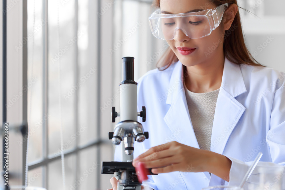 Young attractive Asian woman scientist wearing white lab coat using ...