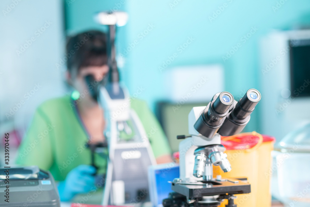 Female professional in uniform. Work with light microscope in research ...