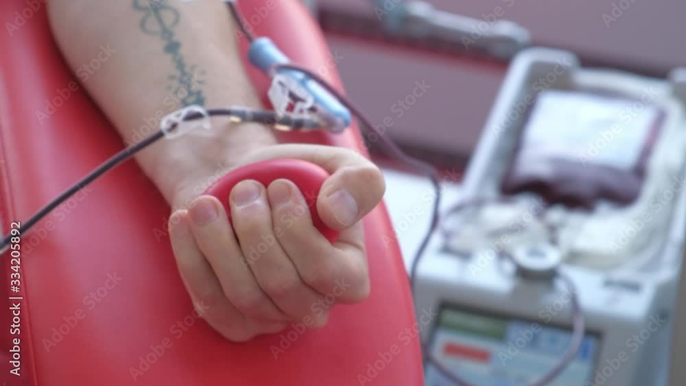donor giving blood, nurse stabs the needle in donors vein, pumping ...