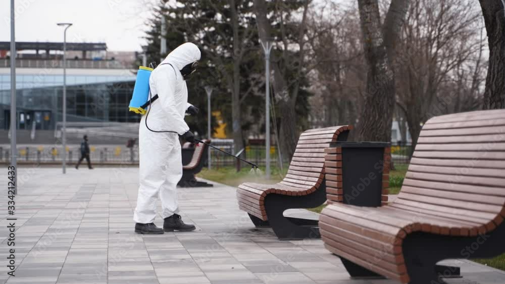 Hazardous materials removal worker disinfects benches with ...