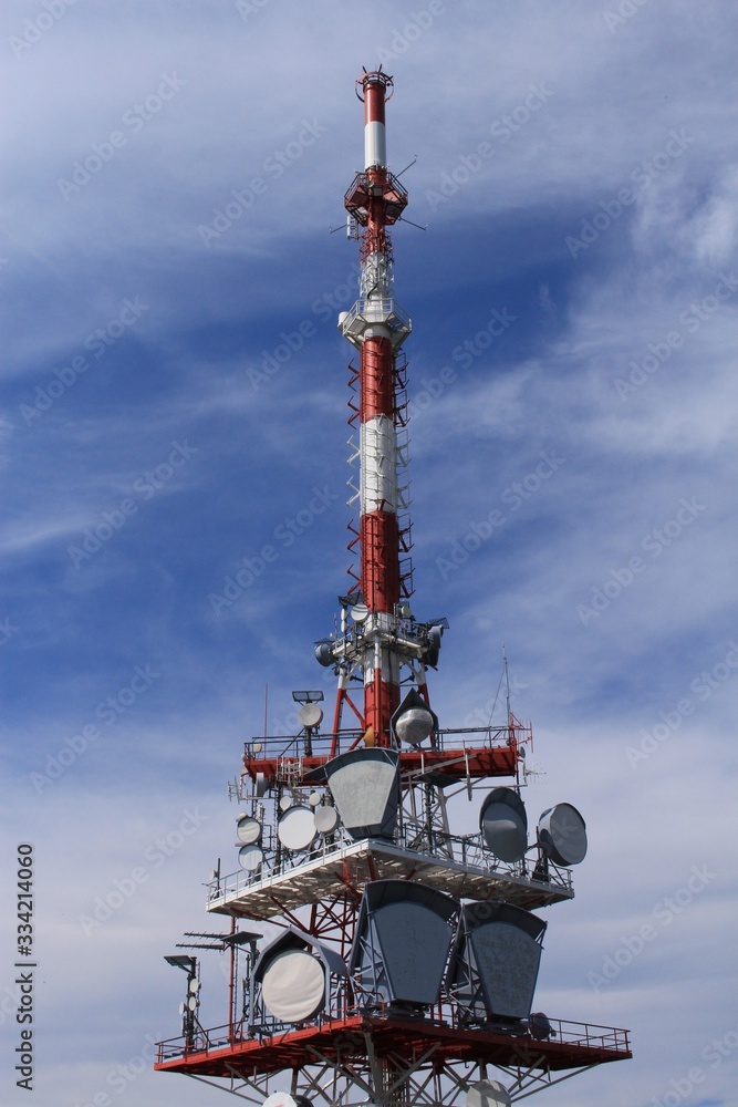 Telecommunication tower with television transmitter antennas on blue ...