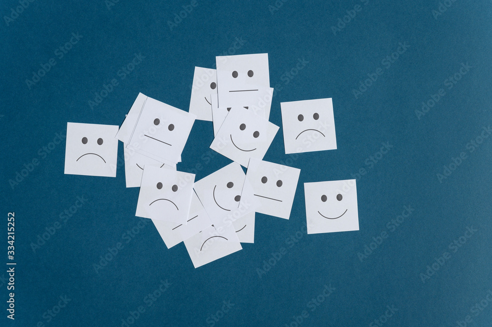 Many white post it papers with smiling sad and neutral faces on them ...