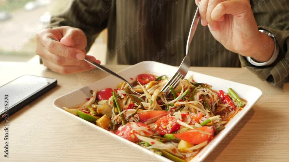 Slow-motion video of a Thai woman using a spoon to scoop the papaya ...