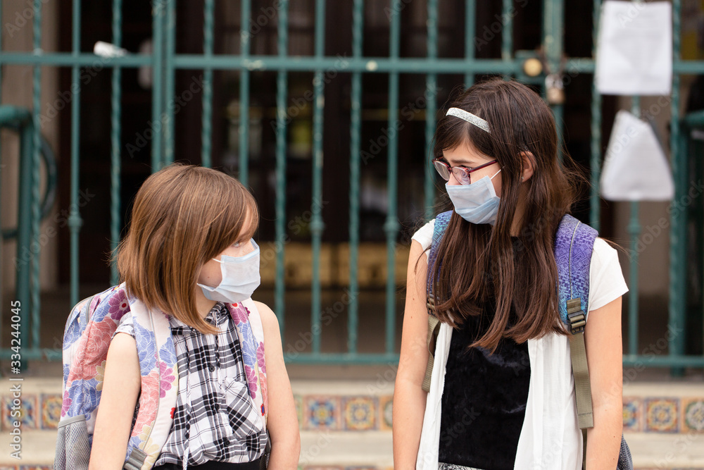 Two school aged girls are in front of the closed and locked school ...