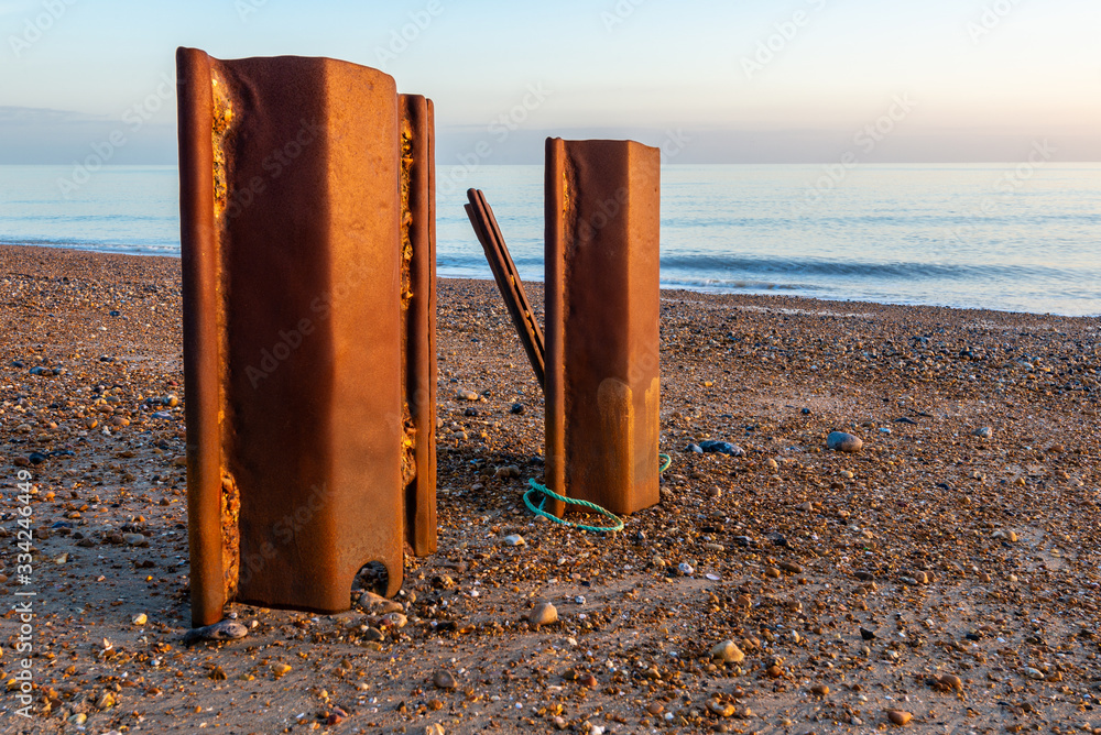 Rotten iron structure forming part of sea defences on a shingle beach ...
