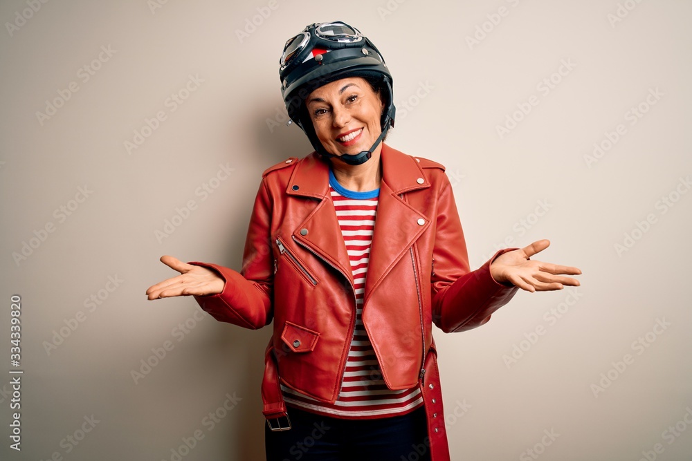 Middle age motorcyclist woman wearing motorcycle helmet and jacket over ...