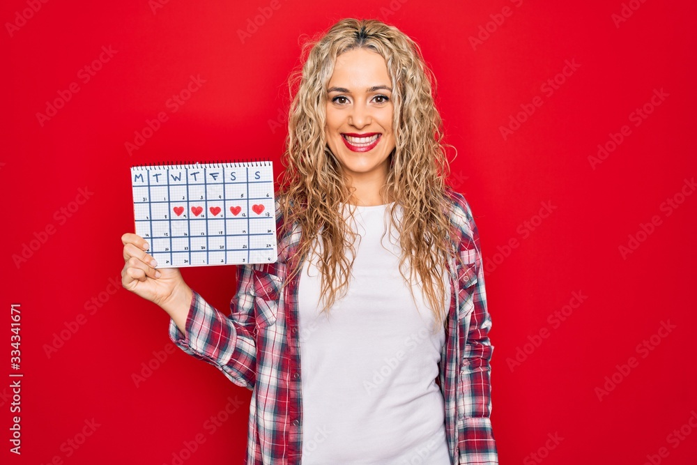 Young beautiful blonde woman holding period calendar controlling ...