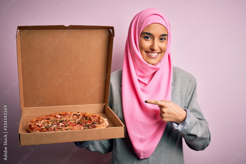 Young beautiful arab woman wearing pink muslim hijab holding delivery ...