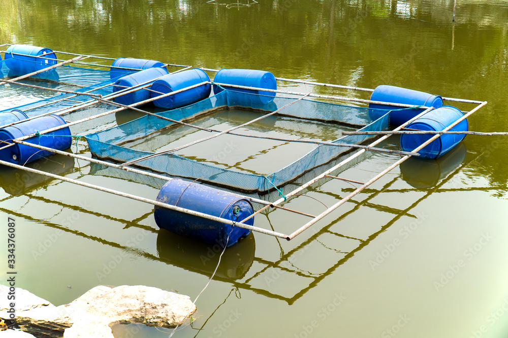 Raising fish in floating net baskets with tank and metal frame. Closeup ...