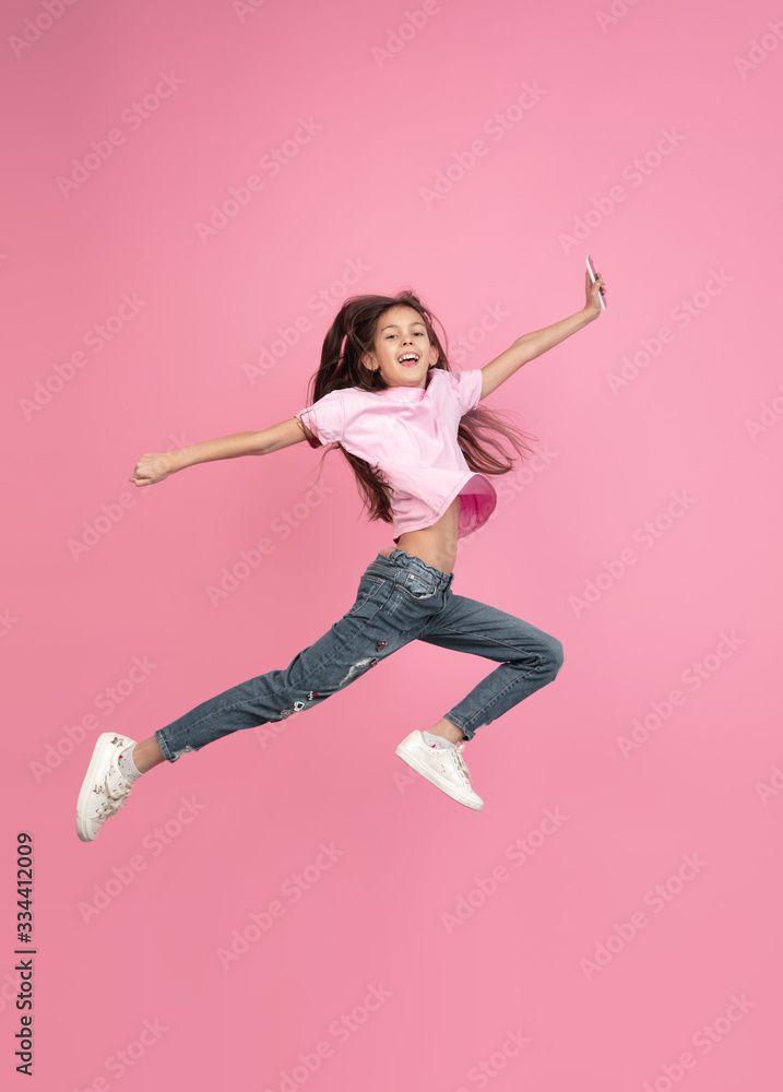 Jumping high. Caucasian little girl portrait isolated on pink studio ...