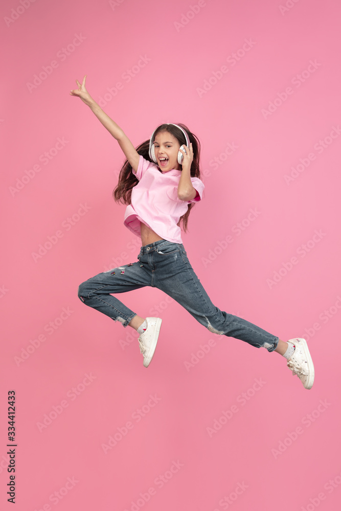 Jumping high with headphones. Caucasian little girl portrait isolated ...