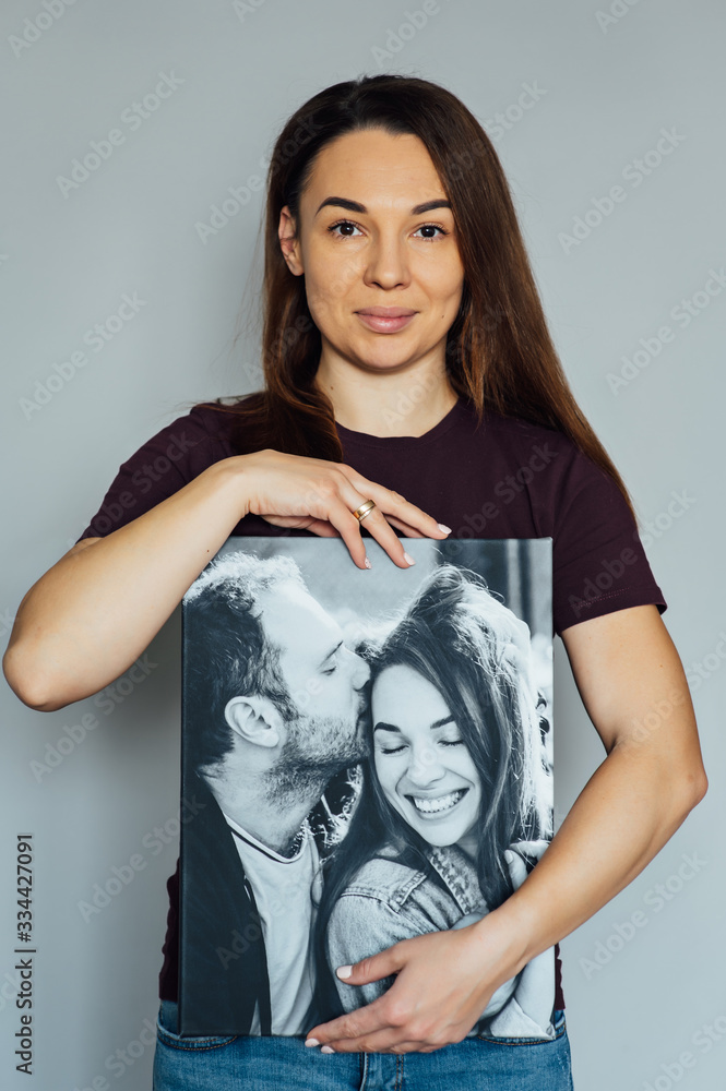 Beautiful girl holds a photo picture in her hands. She depicts her with ...