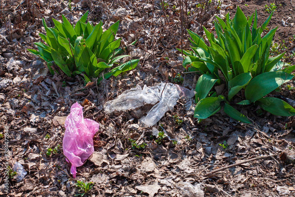 Plastic bags on green grass with tulip flowers in a park. Global trash ...
