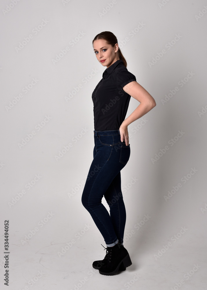 Portrait of a pretty brunette girl with ponytail, wearing jeans boots ...