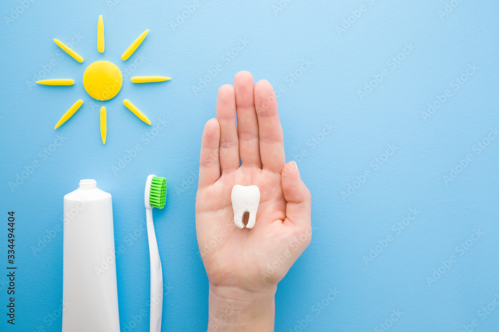 White tooth in young woman hand palm. Toothbrush with green bristles ...