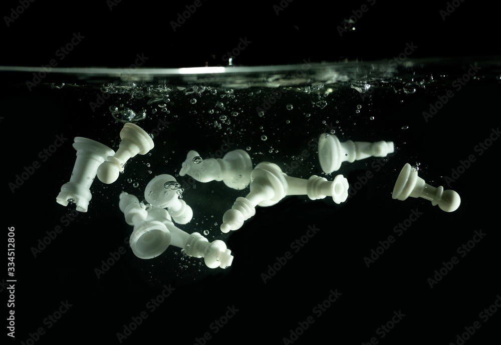 white color chess pieces dropping down in water creating water splash ...