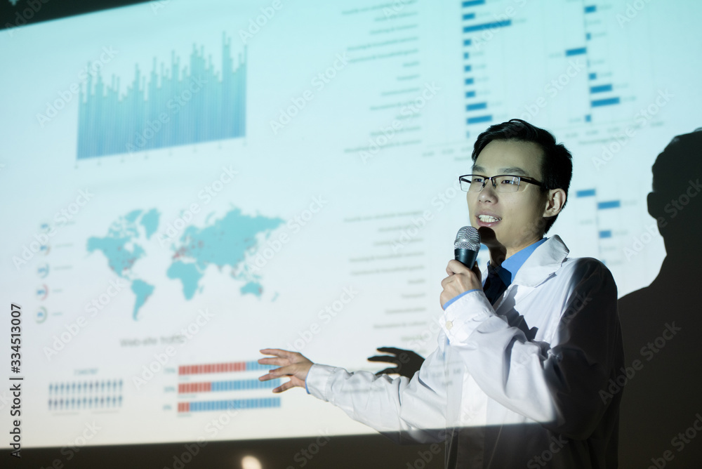 Enterprising young Asian man in glasses and lab coat pointing at ...