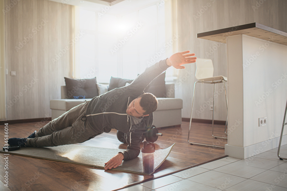 Foto de Young ordinary man go in for sport at home. Bright picture of ...
