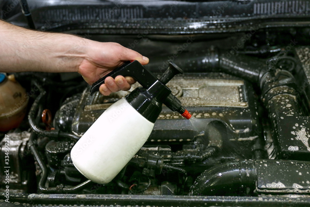car engine washing close-up. mechanic's hand washes a car engine with a ...