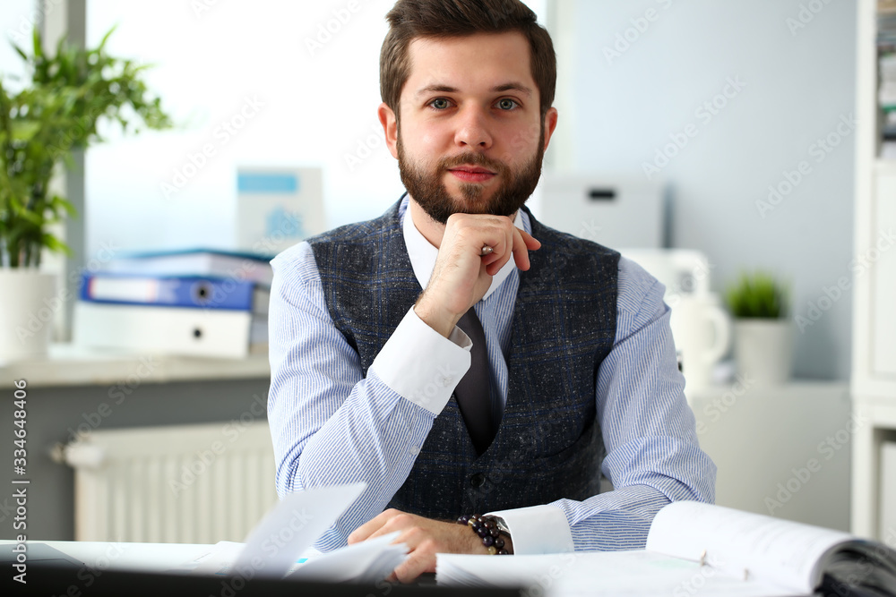 Handsome smiling bearded clerk man at office workplace with silver pen ...