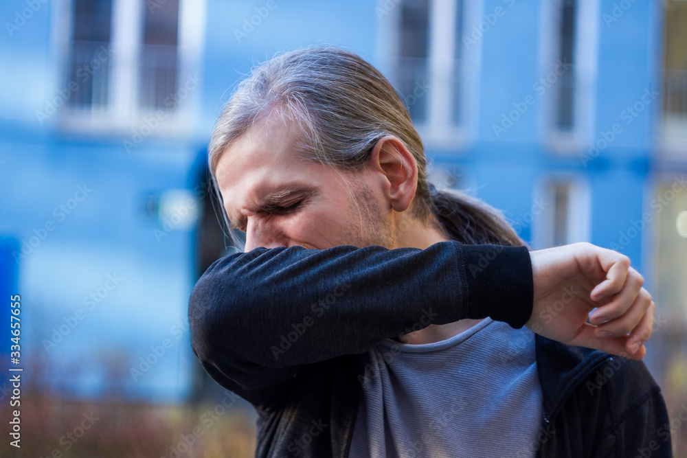Young man is sneezing coughing at elbow to prevent spreading of virus ...