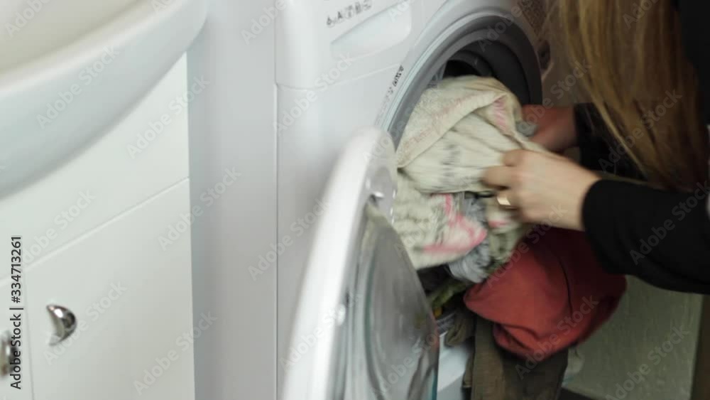 Static view of a woman opening and unloading a washing machine load ...