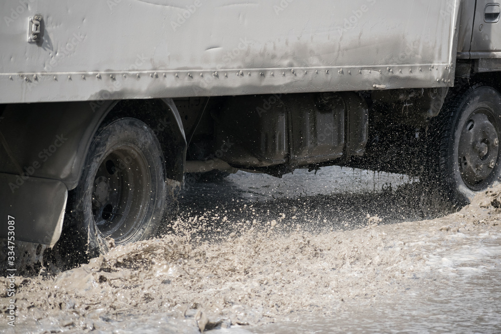 Car motion through big puddle of water splashes from the wheels on the ...