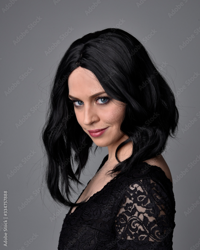 Close up portrait of a pretty, goth girl with dark hair posing in front ...