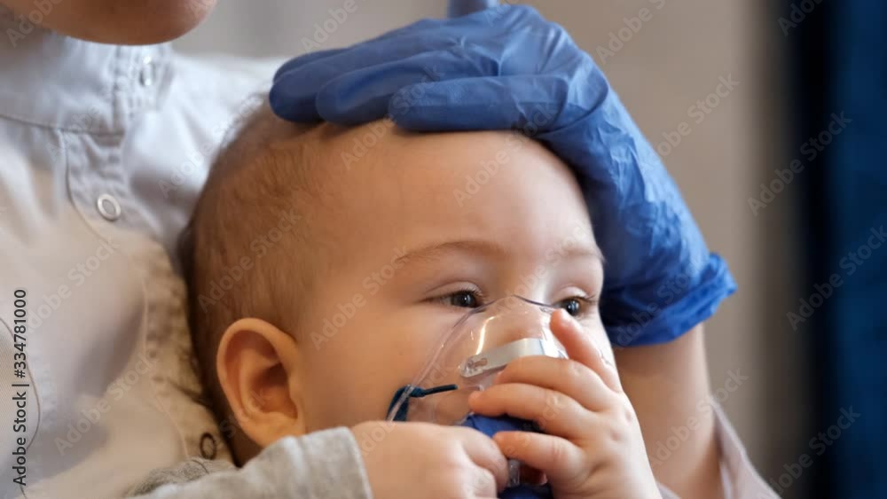 The baby in the hands of a medic is undergoing an inhalation procedure ...
