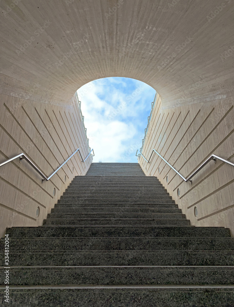 A high stone staircase made of dark granite in a light tunnel of the ...