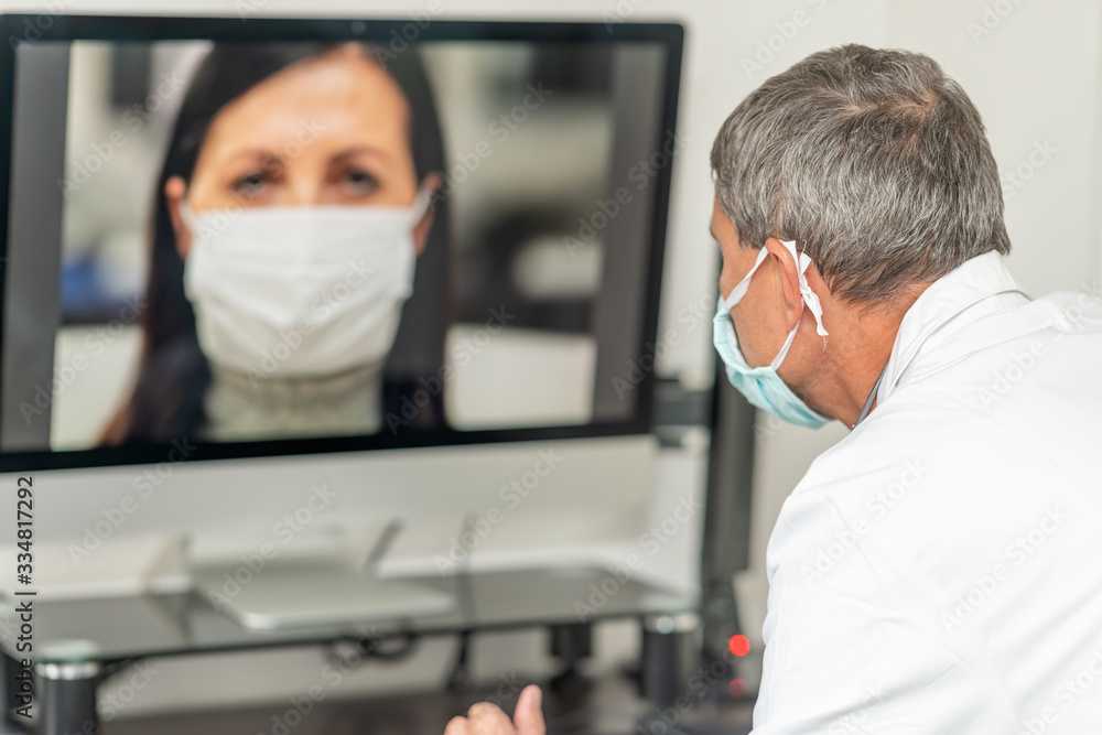 Back view of doctor making video call with his patient at home with ...