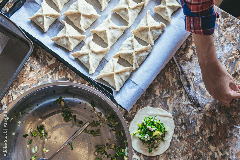Woman cooking pies, also known as somsa, at home, making food from ...