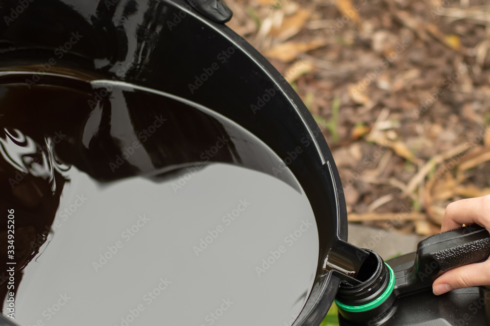 Transfering of used drained motor oil from the black tray to the empty ...