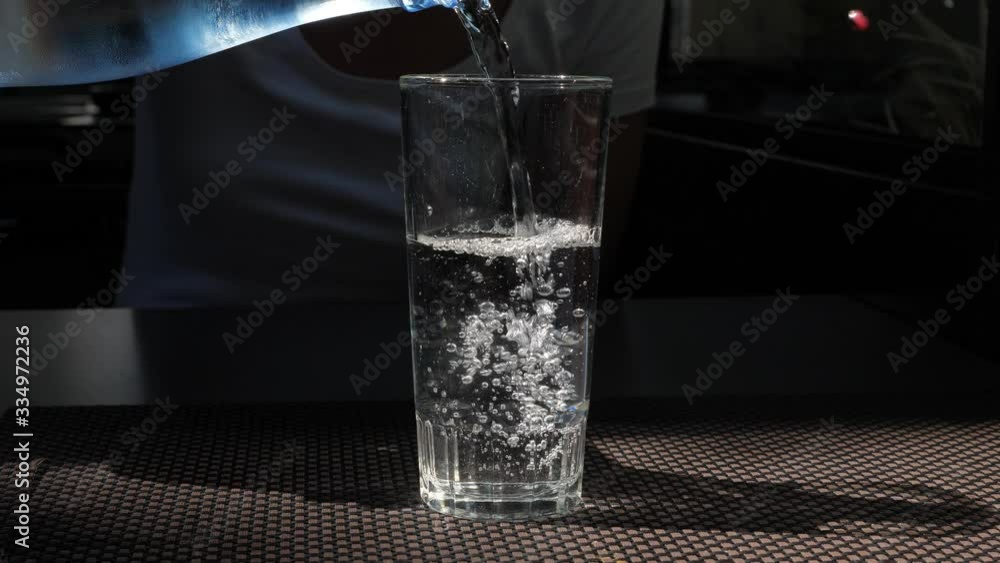 Glass filled to half with pure water from bottle, closeup shot. Woman ...