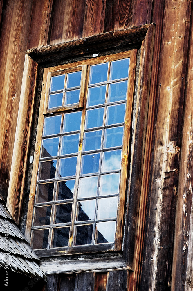 Long vertical window on a brown wooden wall. Reflection of the sky and ...
