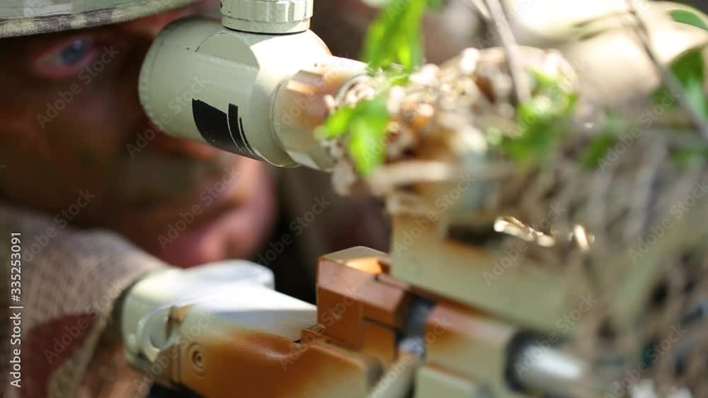 close-up. Soldier looking through sniper scope. Ghillie suit. Tracking ...