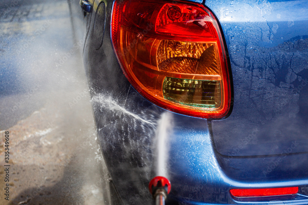 Close-up man holding high-pressure water sprayer for car rear stop ...