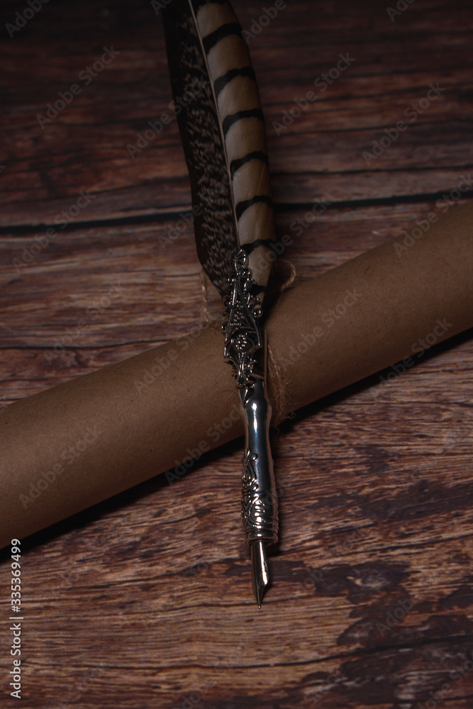 Old quill pen with old paper scroll on the dark wooden table. Letter ...
