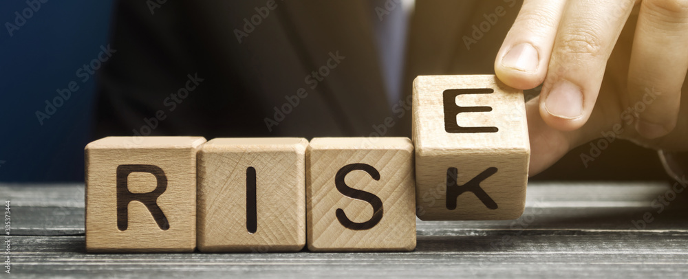 Businessman changes wooden blocks with the words Risk and Rise ...