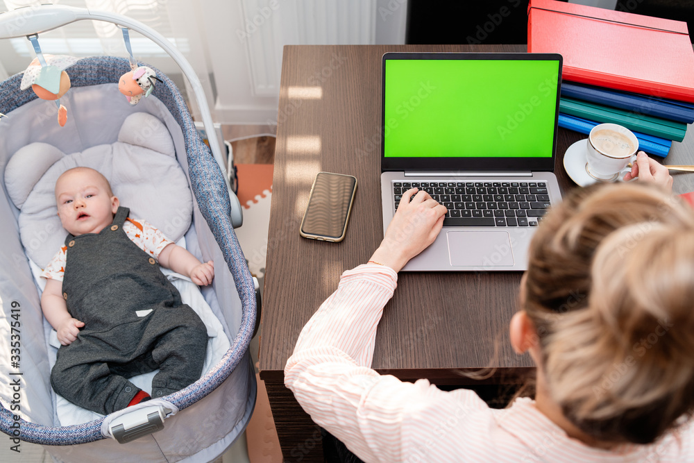 Mom is using a computer and spending time with her cute baby boy at ...