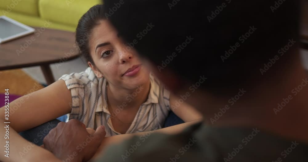 Woman resting her head on her boyfriends lap as he caresses her head they talk in the living ...