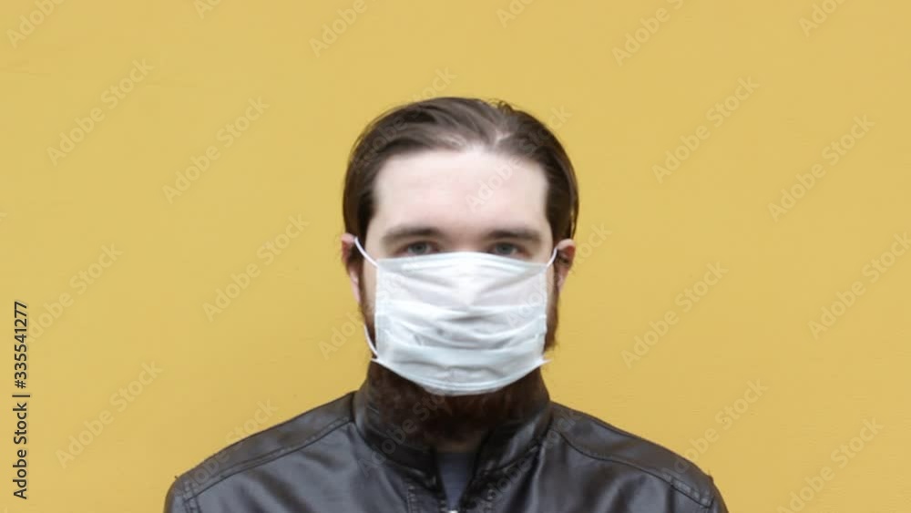 man puts on and removes a disposable mask to protect against the ...