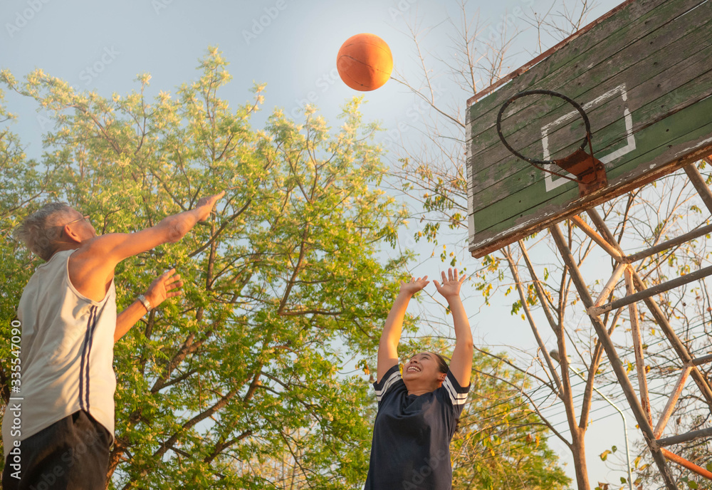 Asian elderly men playing basketball with daughter on playground on ...