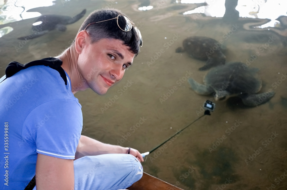 Young brunette guy with camera releases turtle into water, volunteer ...